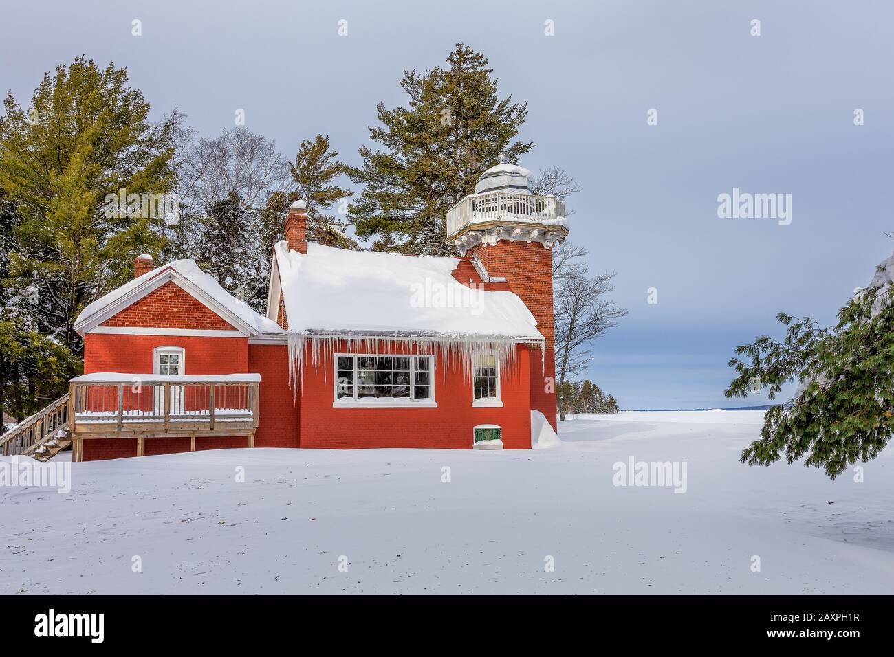 Red brick lighthouse set in deep snow and surrounded by green pine ...