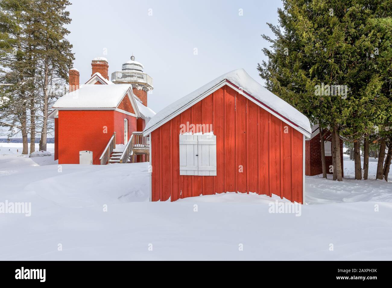 Red buildings with white shutters set in deep snow and framed by green ...