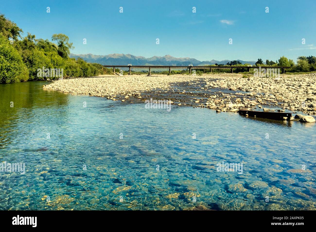 crystal clear water flowing in a rural river under a steel railway ...