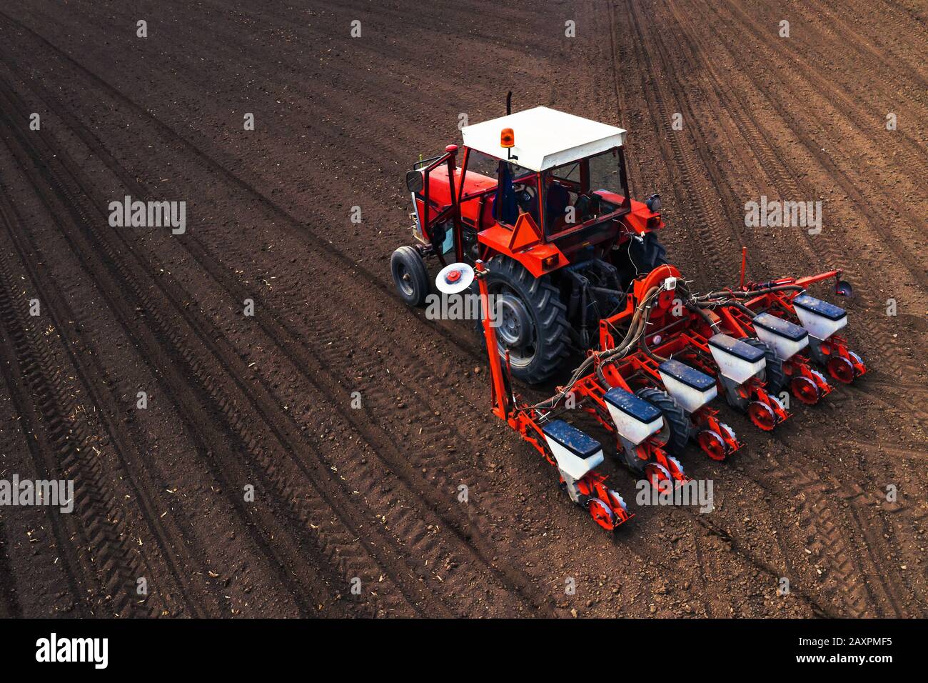 Aerial view of tractor with mounted seeder performing direct seeding of ...