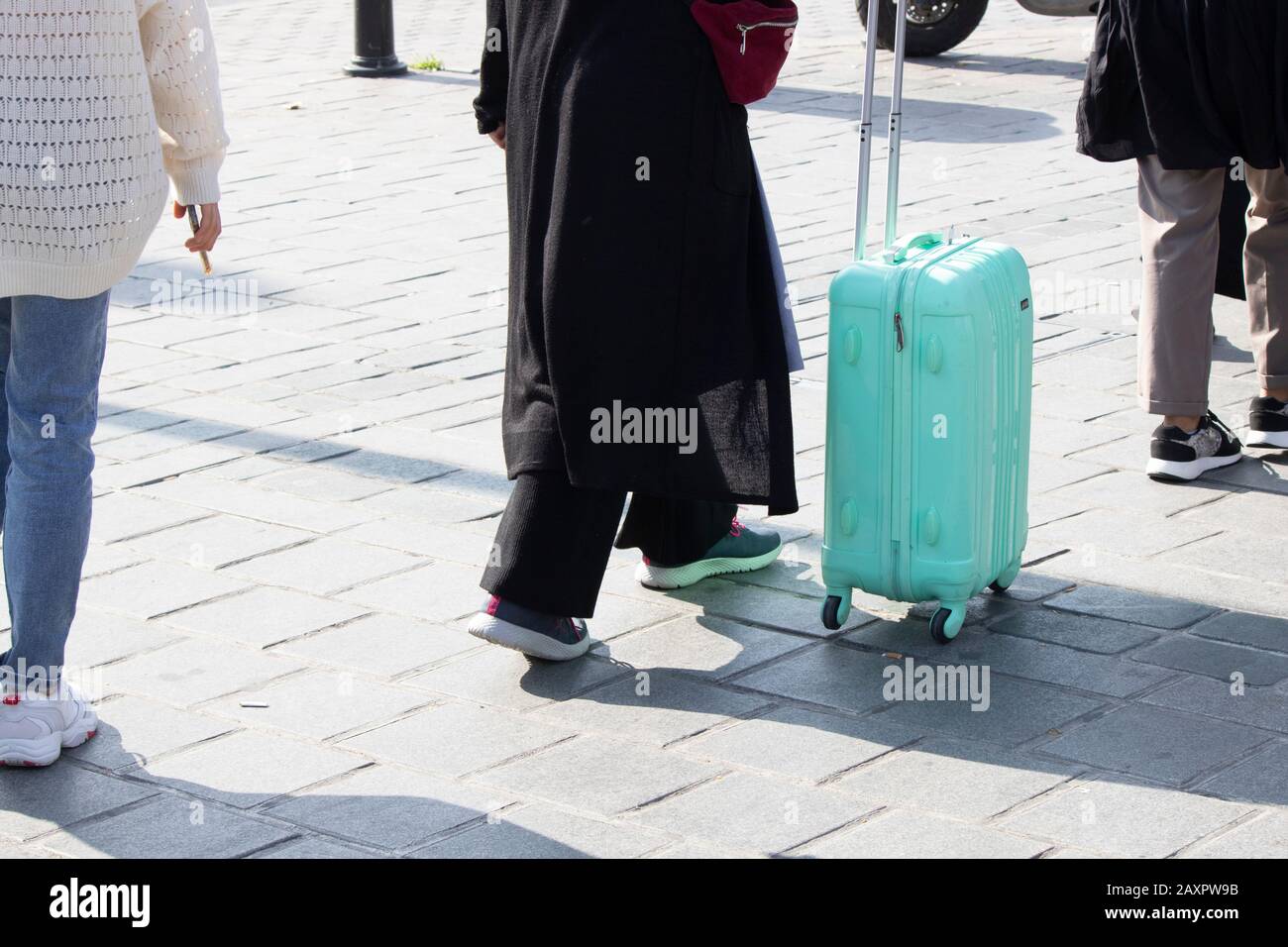 Turquoise suitcase in the hands of a tourist. Photographed in the ...