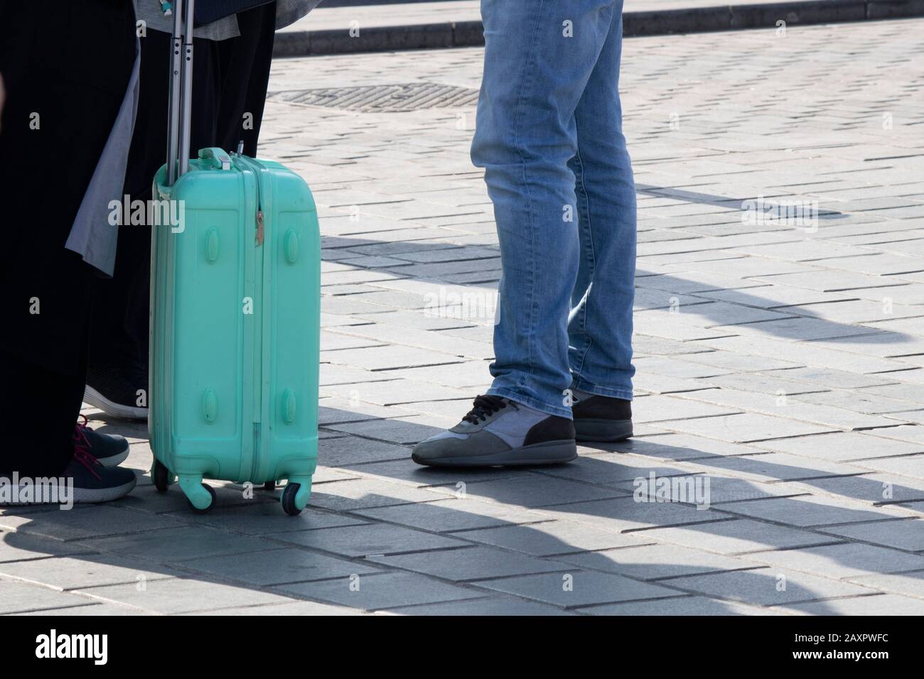 Turquoise suitcase in the hands of a tourist. Photographed in the ...