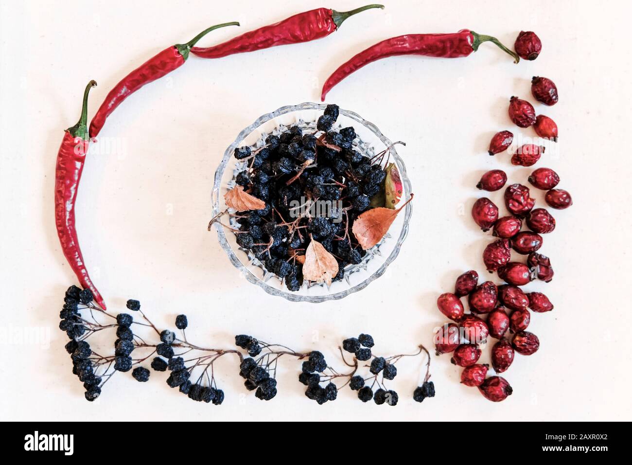 Dried red chili peppers, rose hips, black aronia on white background ...