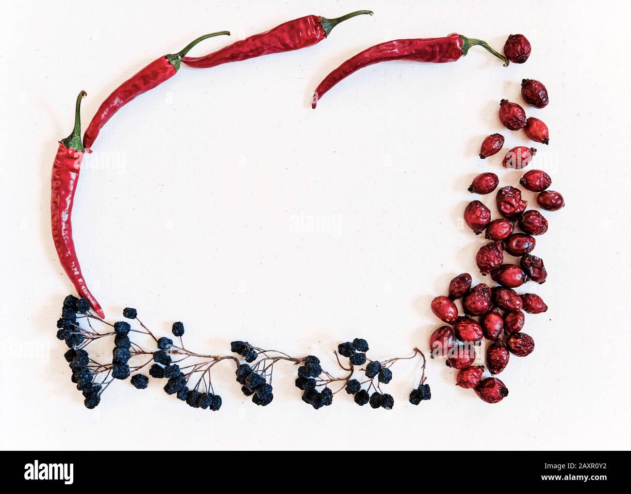 Dried red chili peppers, rose hips, black aronia on white background ...