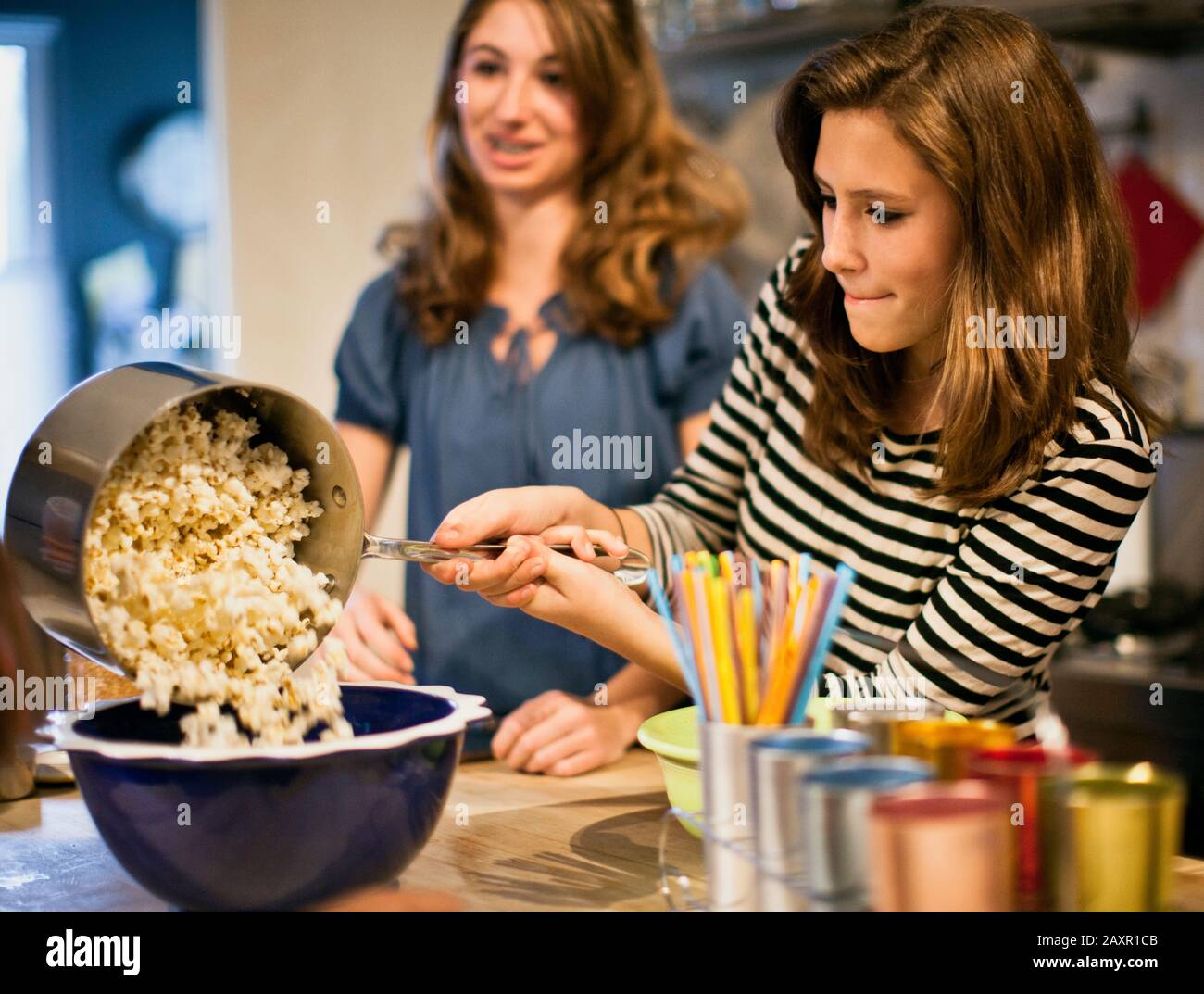 Teenage girl pouring popcorn into bowl Stock Photo - Alamy