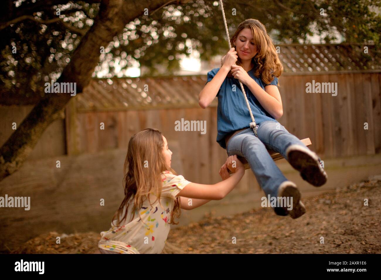 Teenage girl pushing friend on rope swing Stock Photo - Alamy