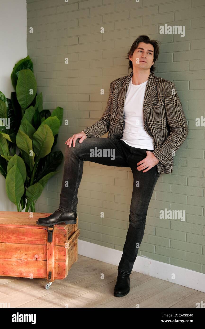 Tall handsome man standing next to grey wall and wooden box Stock Photo ...