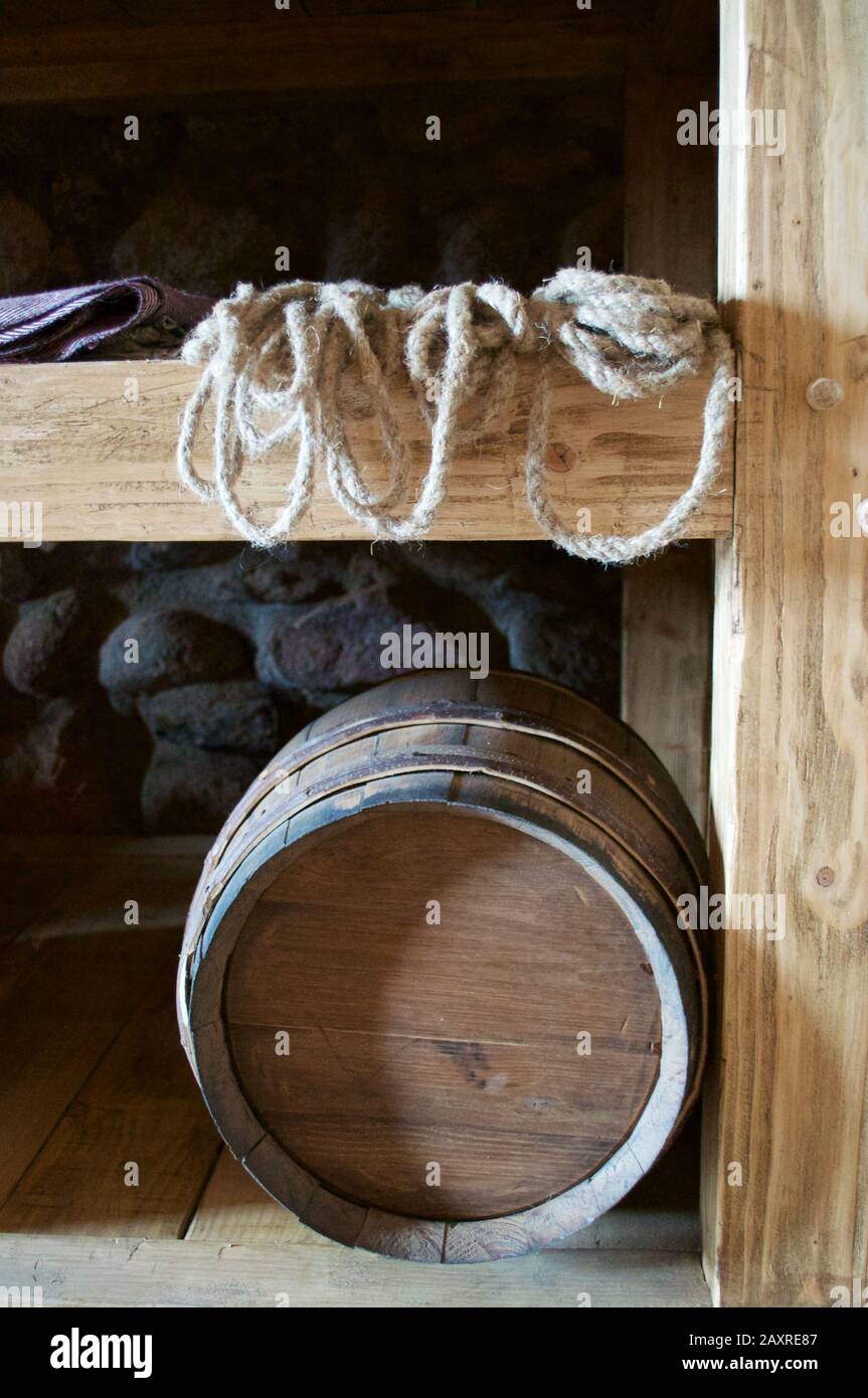 A wine barrel, a thick rope, and a purple cloth on a shelf against the ...