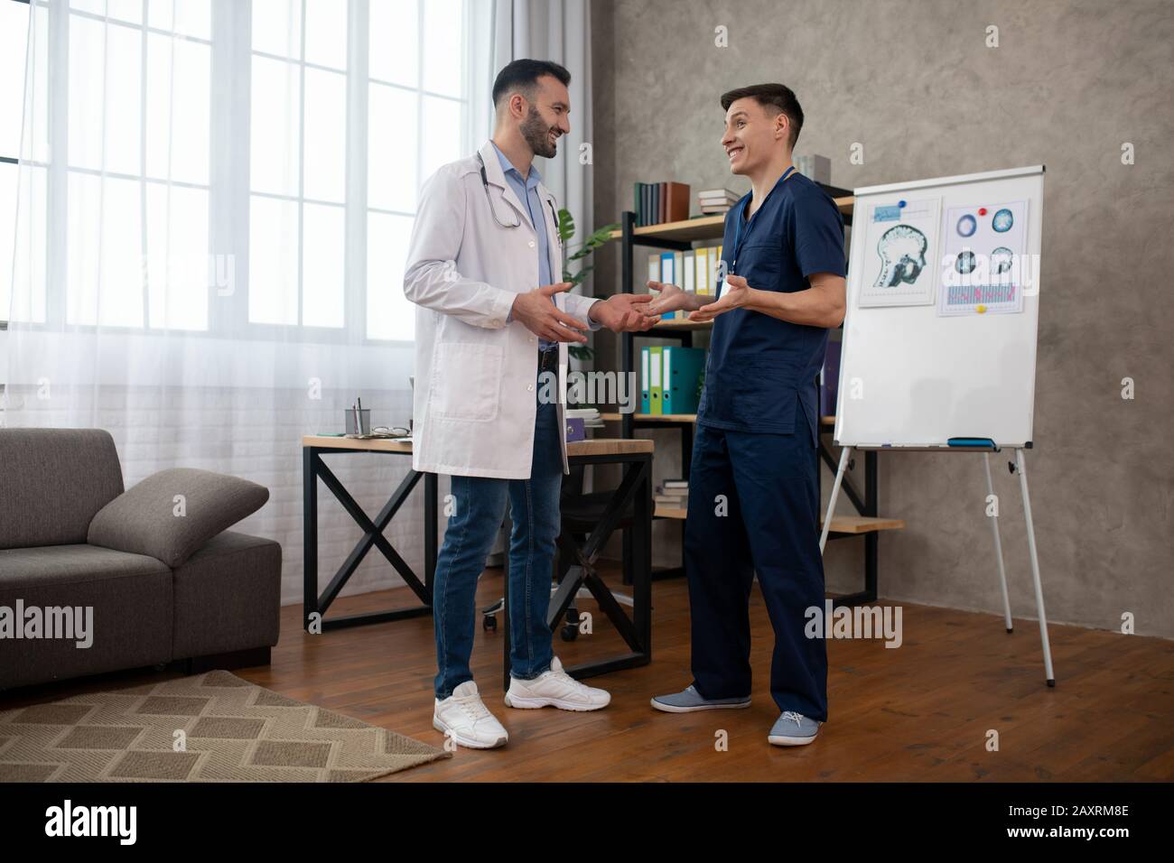 Two doctors talking during changeover and looking positive Stock Photo ...
