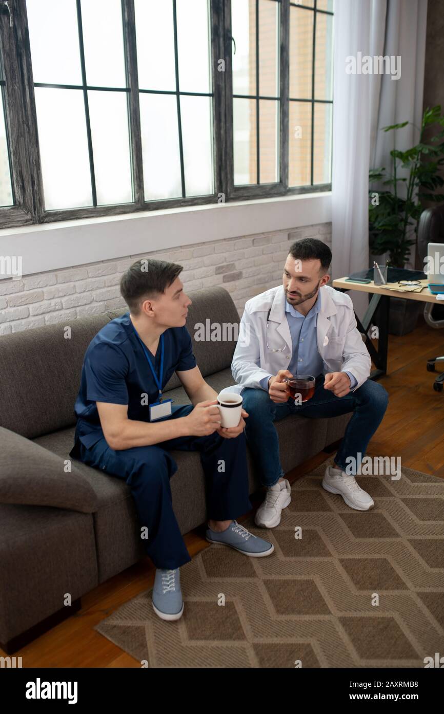 Two doctors having tea and talking during changeover Stock Photo - Alamy