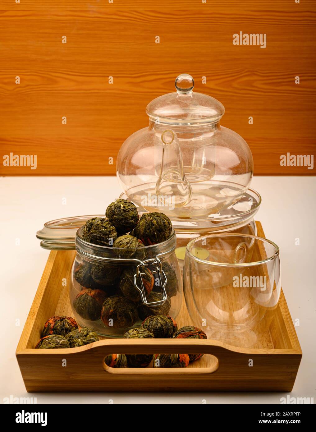 Flower tea balls in a glass jar, a glass teapot and a glass on a wooden ...