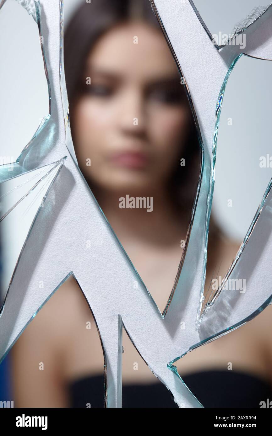 Young woman looks in a broken mirror. Out of focus blurred, portrait of ...