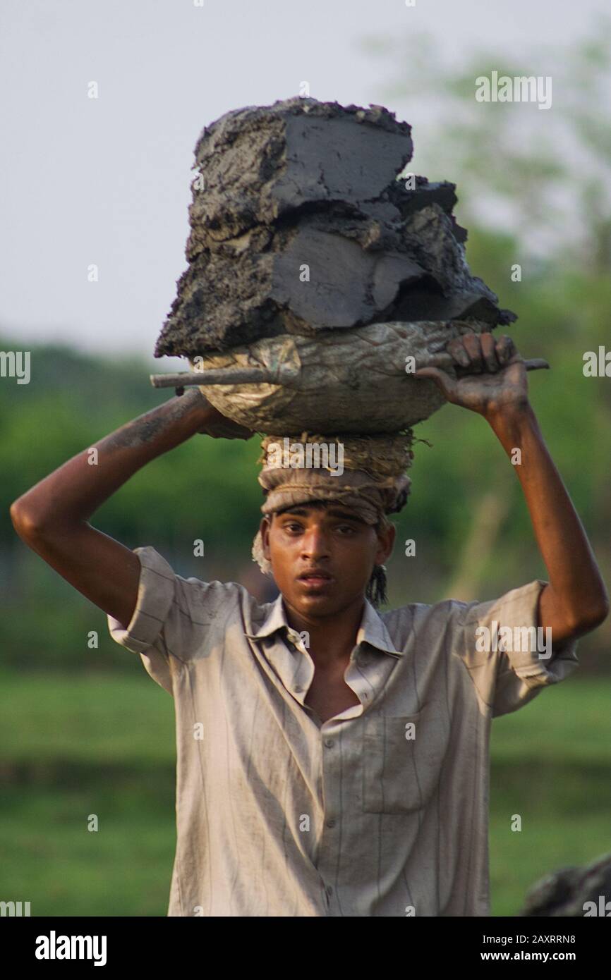 A day labourer carries a basket of soil on his head. Khulna, Bangladesh ...