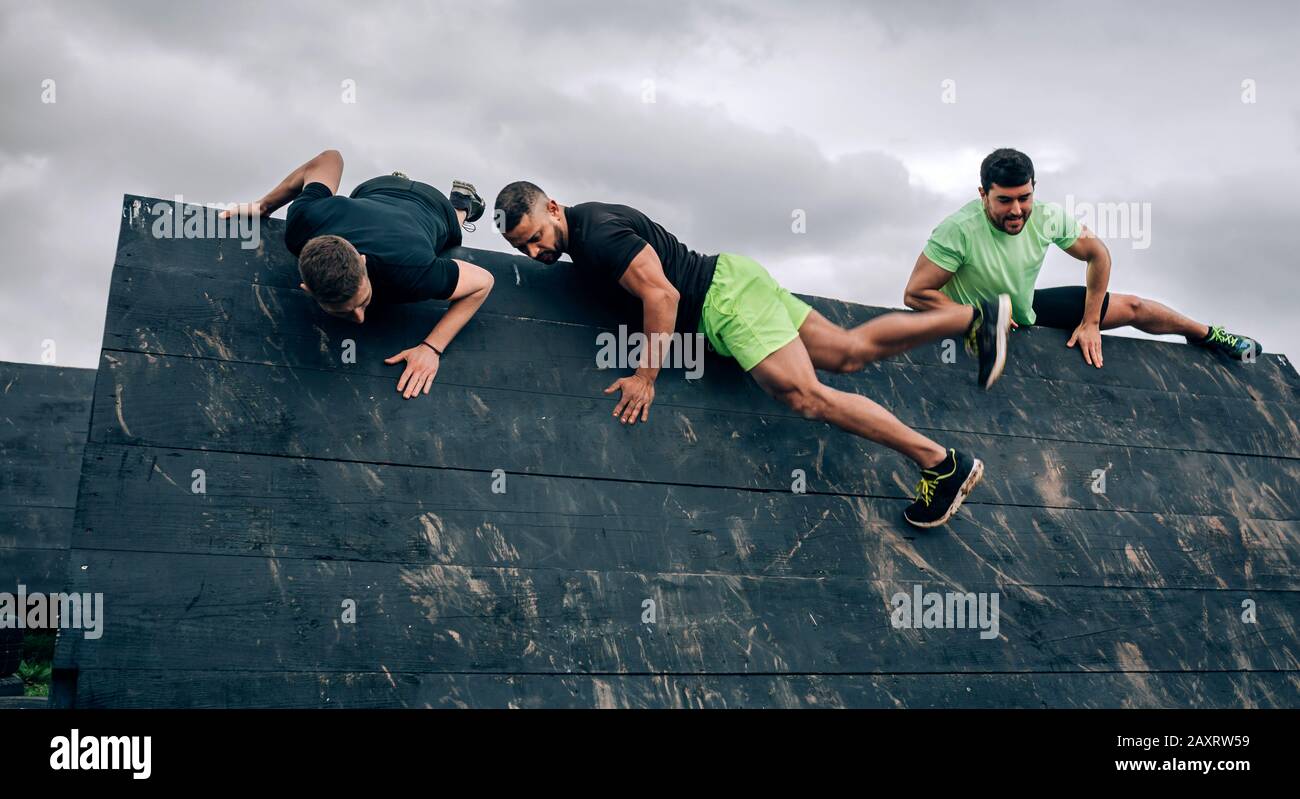 Participants in obstacle course climbing wall Stock Photo - Alamy