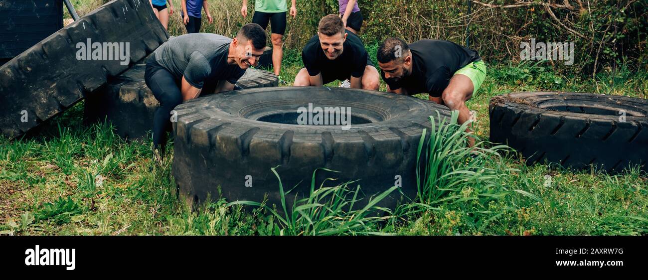 Participants in an obstacle course turning a wheel Stock Photo - Alamy