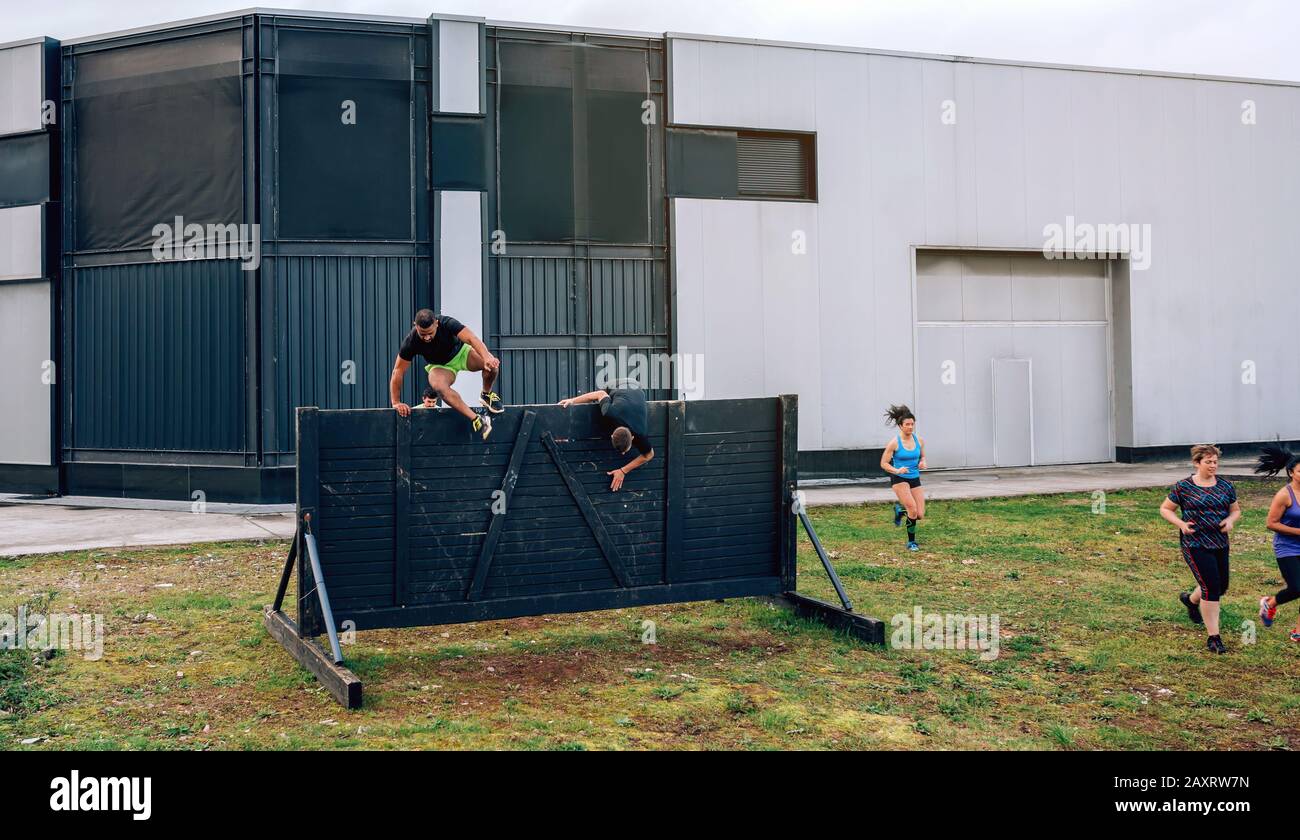 Participants in obstacle course running and climbing wall Stock Photo ...