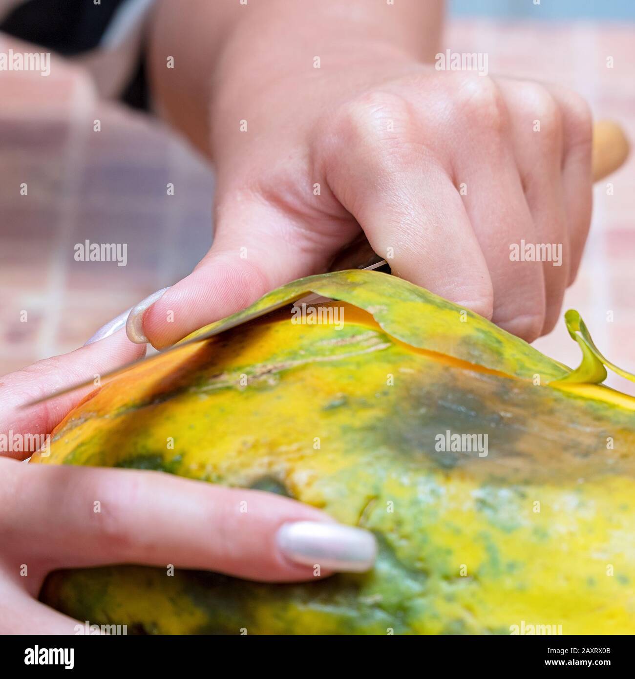 Woman cleans papaya fruit from the peel. Peel the papaya Stock Photo ...