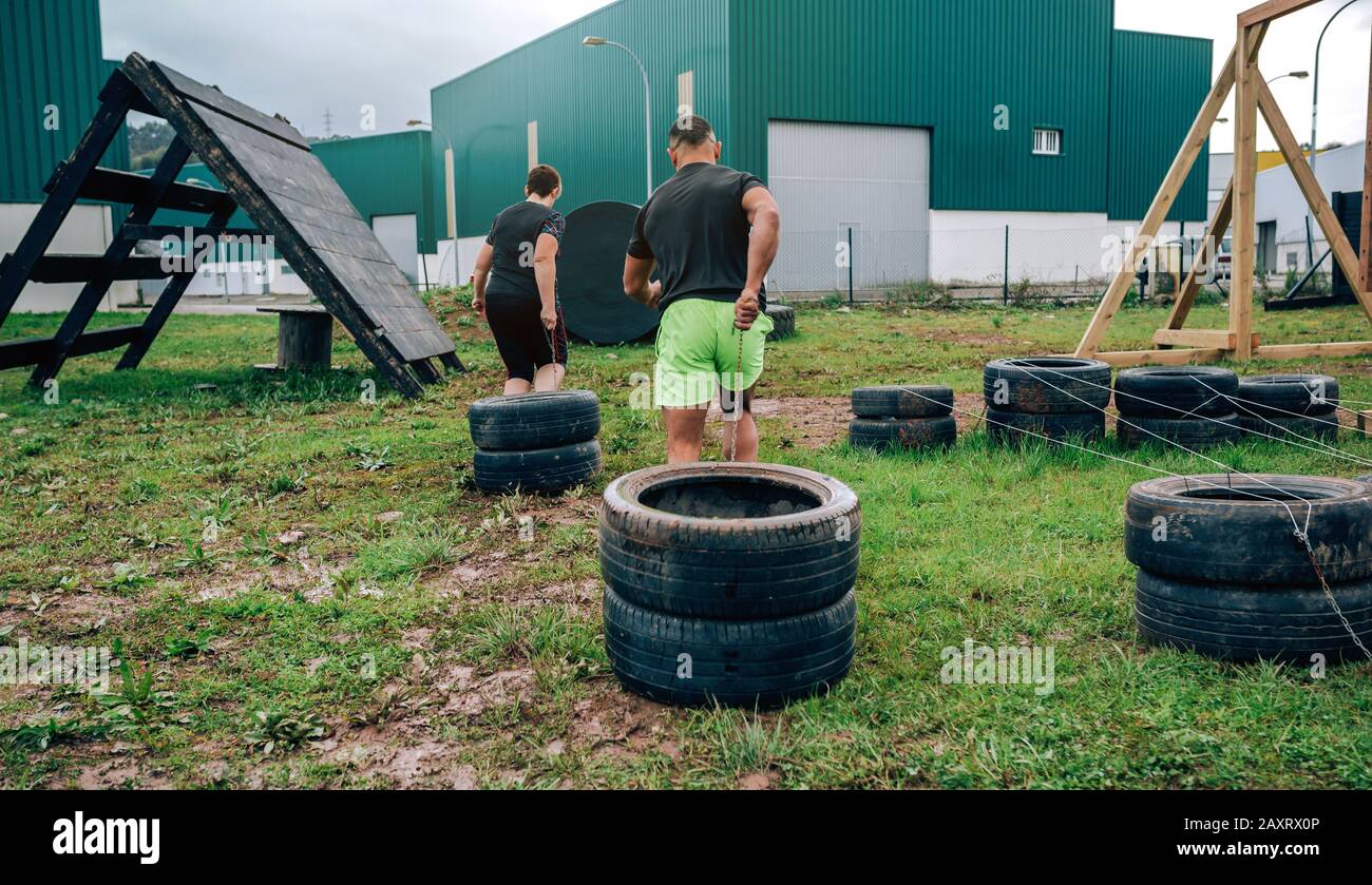 Participants in an obstacle course dragging wheels Stock Photo - Alamy