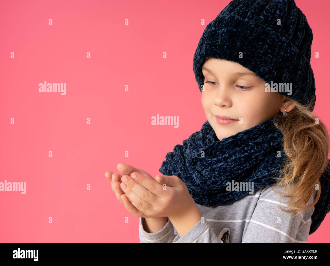 Cute little lady in a warm hat and scarf, having something in her hands ...