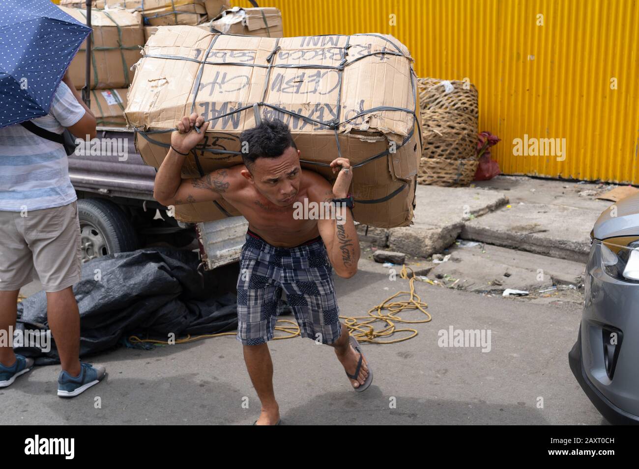 A Filipino man carries a heavy load of goods within a market area of ...