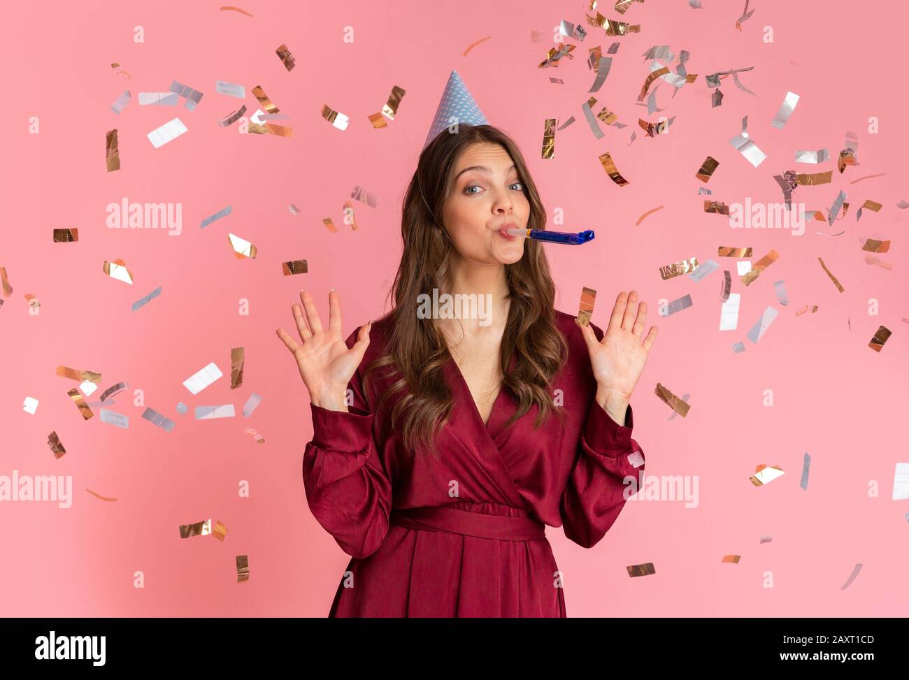 Excited girl standing under confetti with birthday hat and party ...
