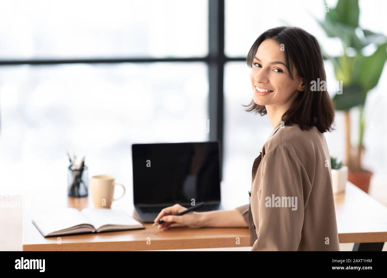 Smiling young teacher with blank screen laptop at office Stock Photo ...