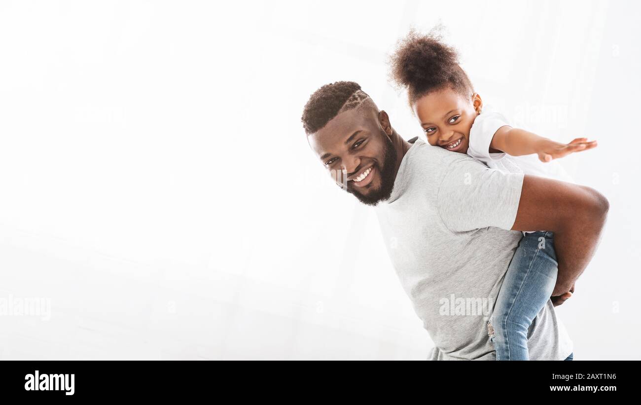 Happy black father holding his little daughter on his back Stock Photo ...