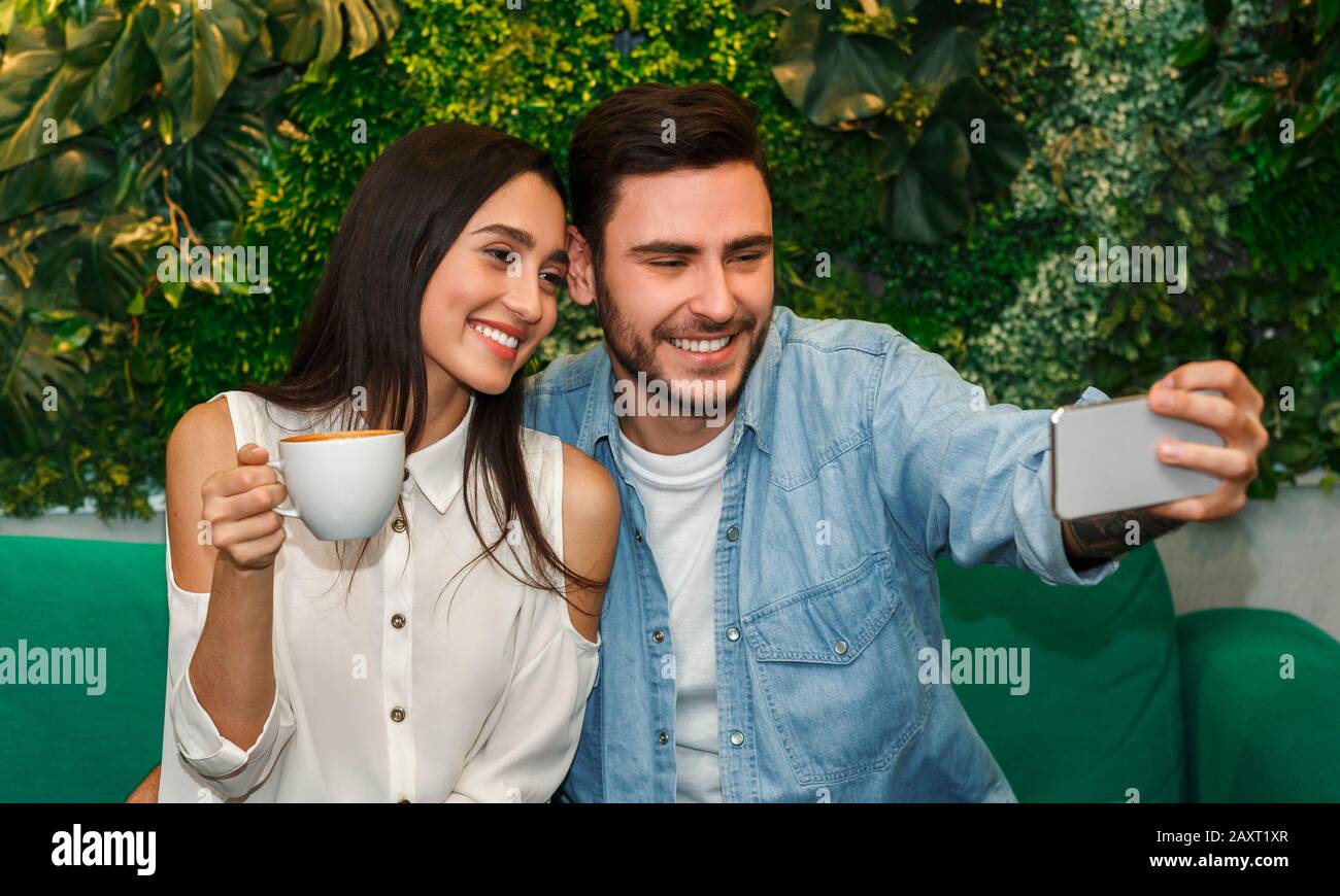 Cheerful Couple Making Selfie Hugging And Having Coffee In Cafeteria ...
