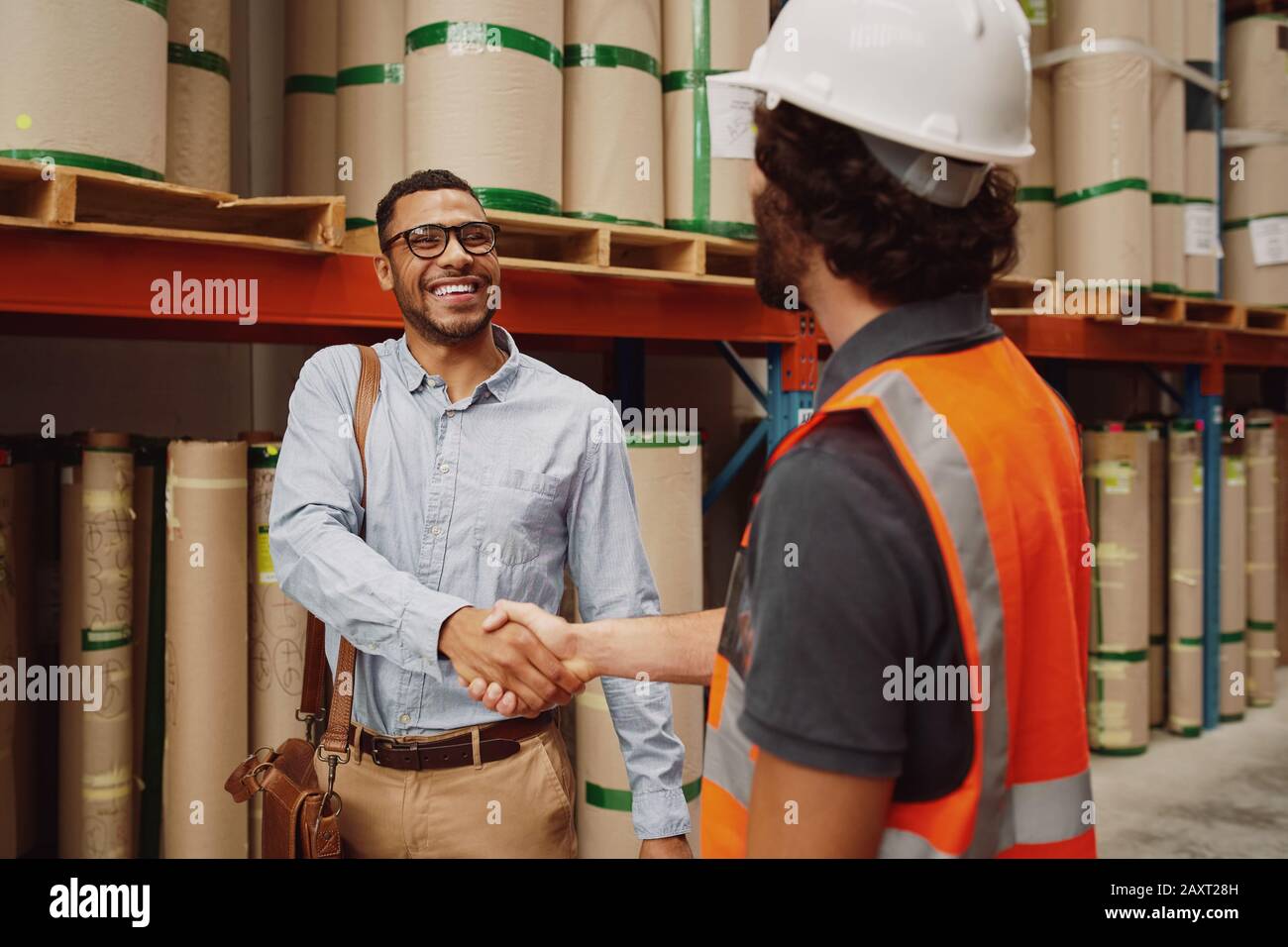 Happy banker in formal clothing shaking hands with warehouse manager ...