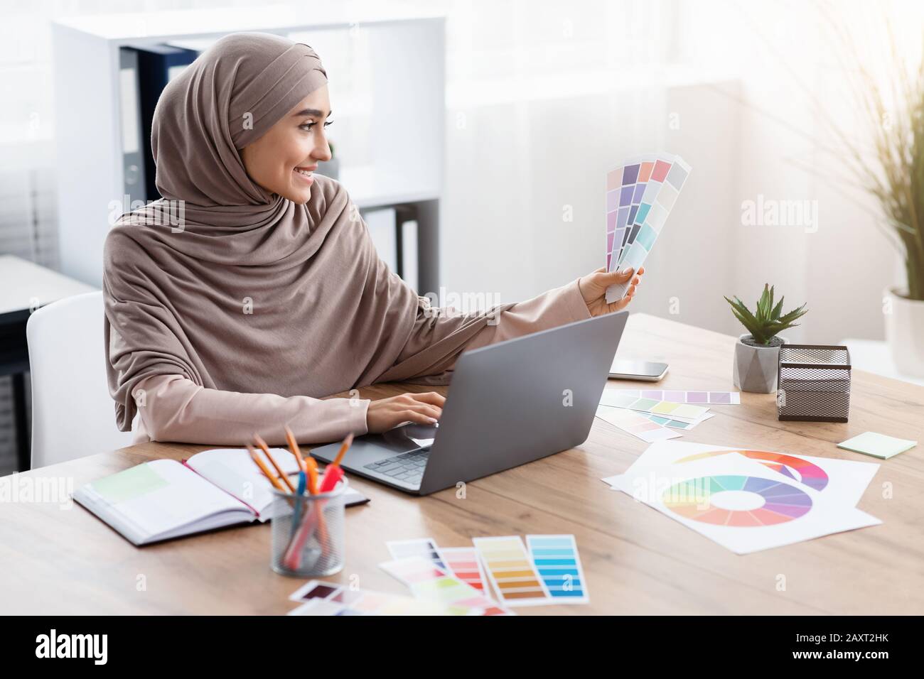 Muslim female designer working with color palette and laptop in office ...