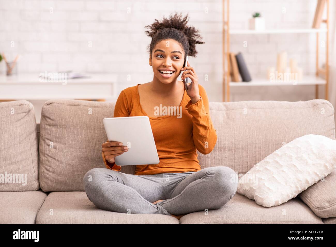 Black Woman Talking On Phone Using Tablet Sitting On Sofa Stock Photo ...