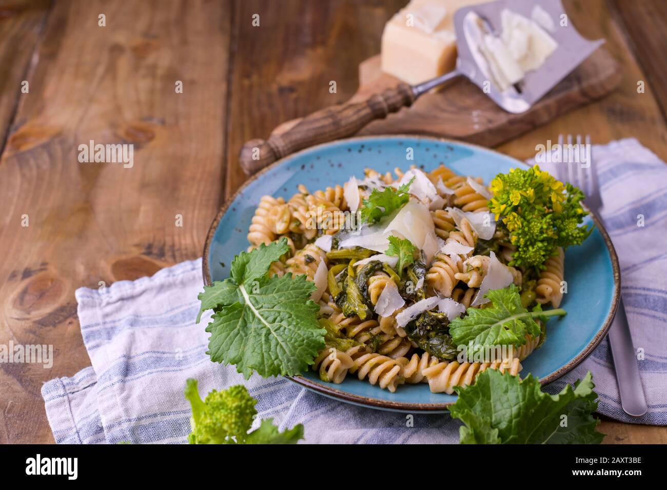 Cime di rapa pasta in a plate on with parmesan on a wooden table ...