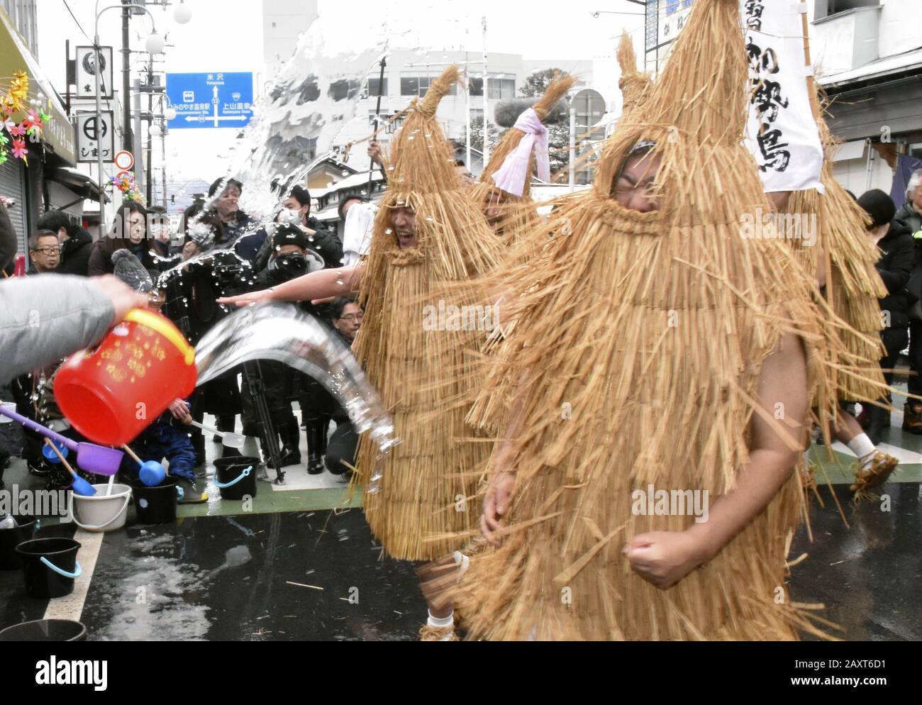 People splash water on participants of a folk festival dressed in straw ...