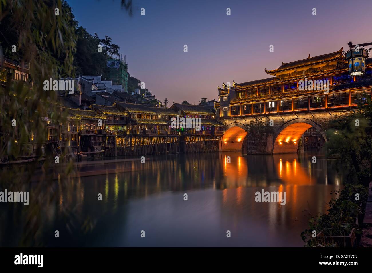 Illuminated at night old historic arched bridge on the riverbanks of ...
