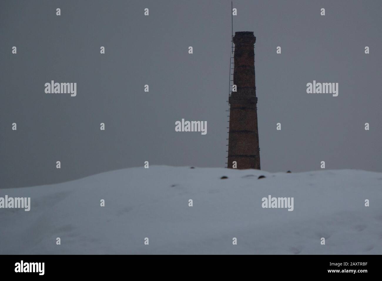 Pipes of a plant on a background of gray sky. Brick pipes peep out from ...