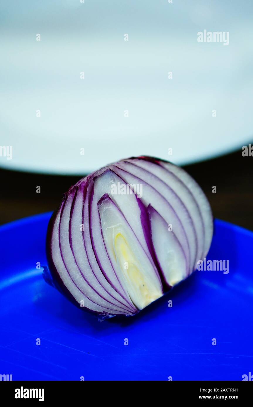 Vertical closeup shot of half of a red onion with a blurred background ...