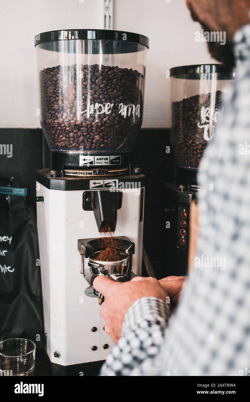 Vertical shot of a man grinding coffee beans with a machine Stock Photo ...