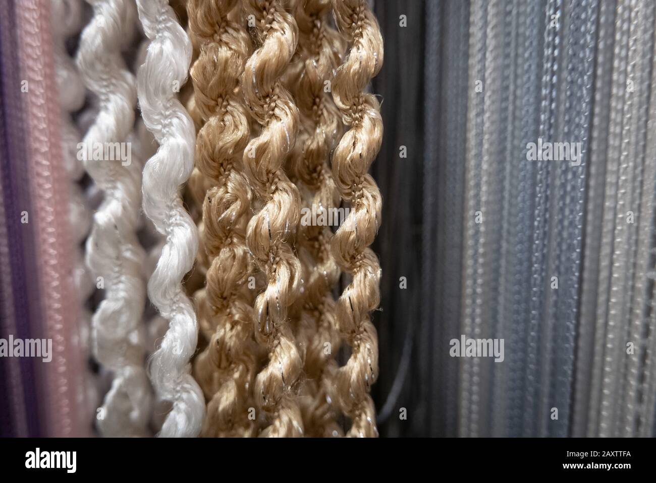 Textile strings and ropes hangs in a fabric shop. Abstract background ...