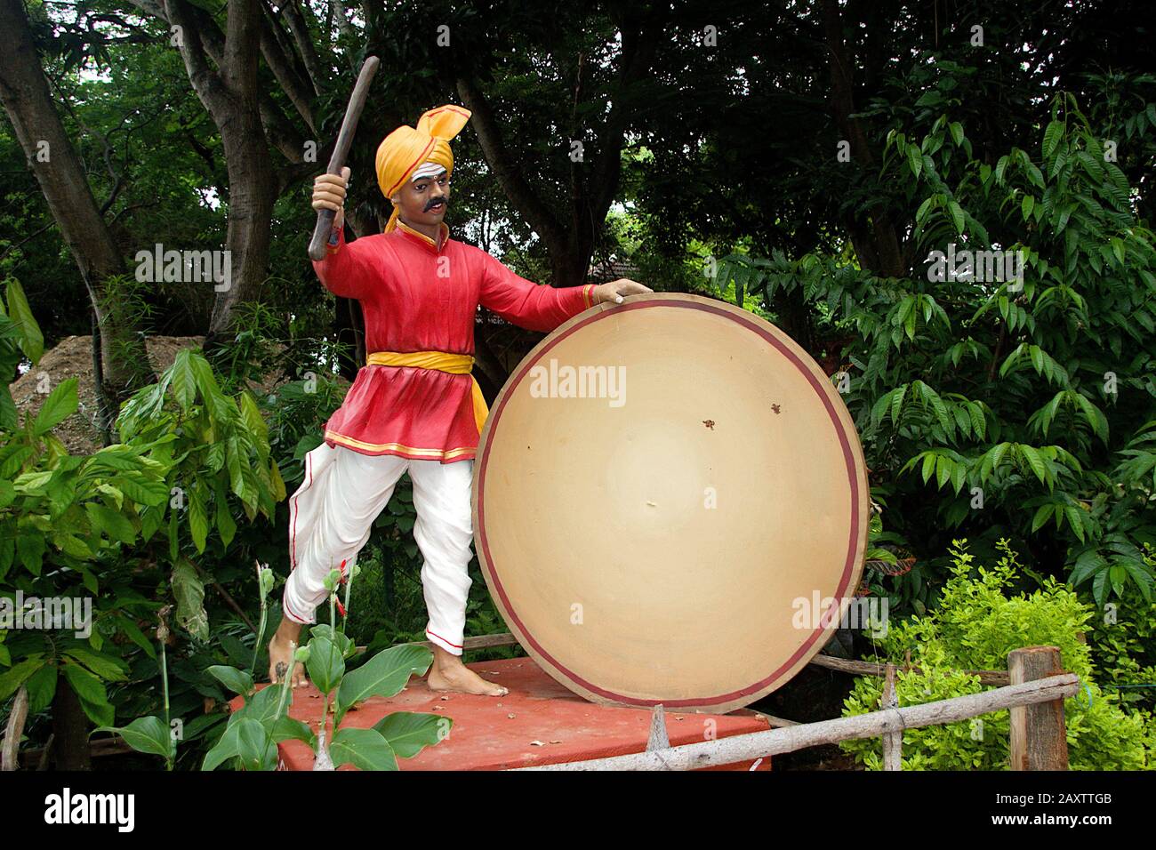 Life size icon of folk artist beating huge leather covered wheel called ...