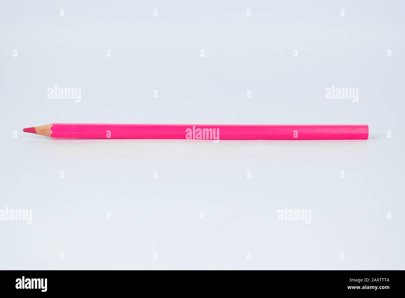 Single pink colored sharp wood pencil crayon placed on an isolated ...