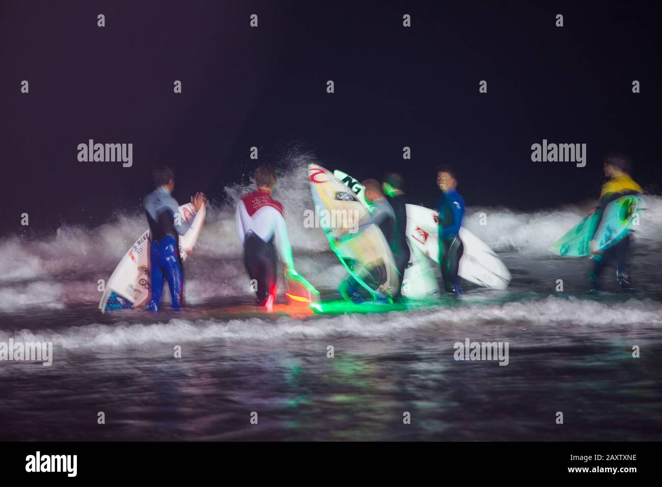Surfers going surfing at night with neon surfboards Stock Photo - Alamy
