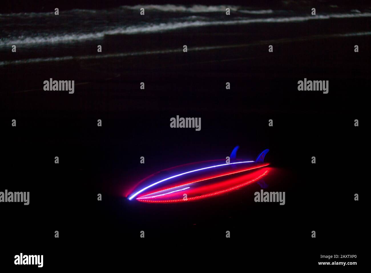 Neon surfboard in the sand at night Stock Photo - Alamy