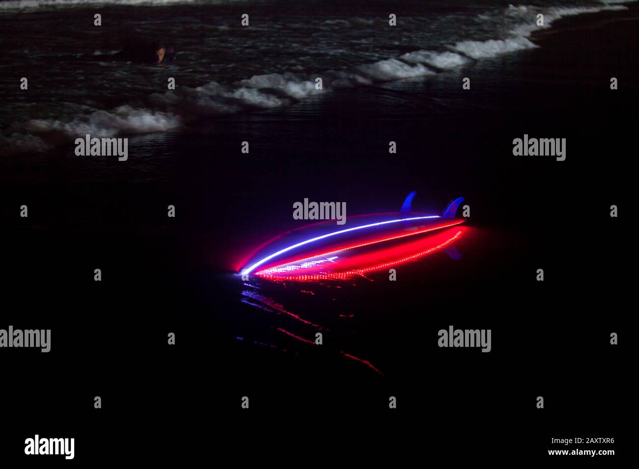 Neon surfboard in the sand at night Stock Photo - Alamy