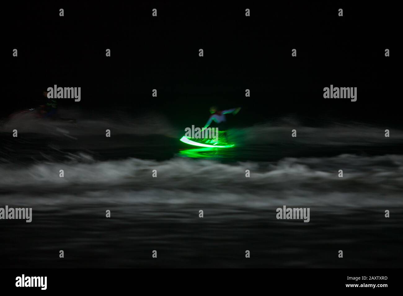 Surfing a neon surfboard at night Stock Photo - Alamy