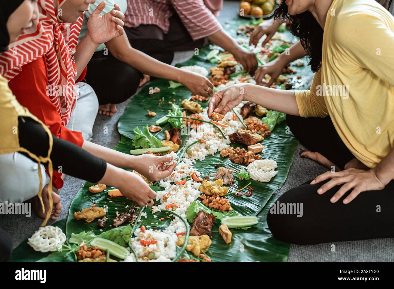 gesture of woman hand eating their food together laying on banana leaf ...