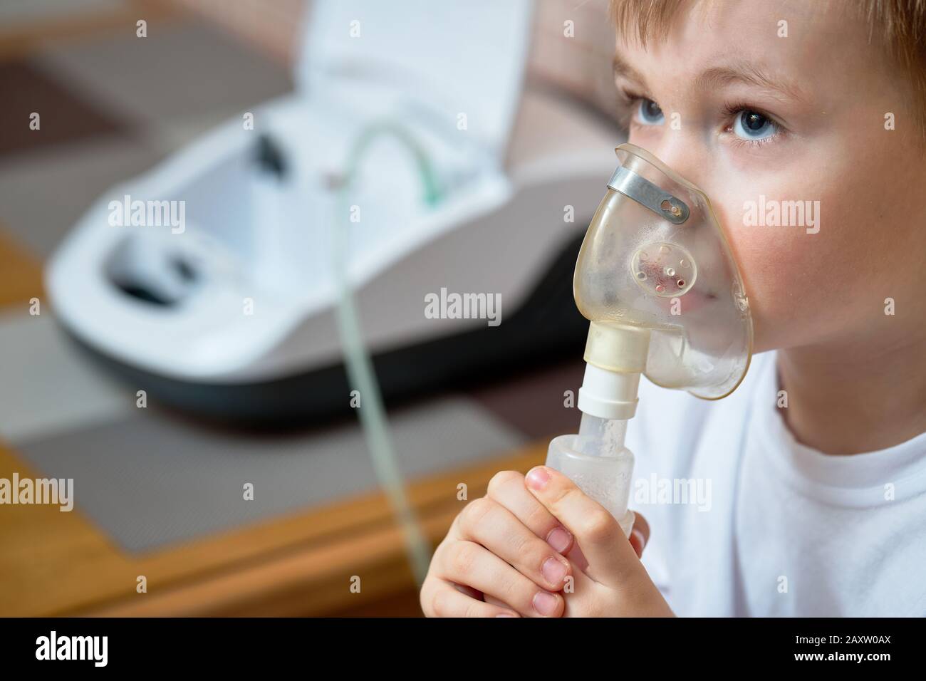 Child makes inhalation at home with nebulizer on out of focus ...