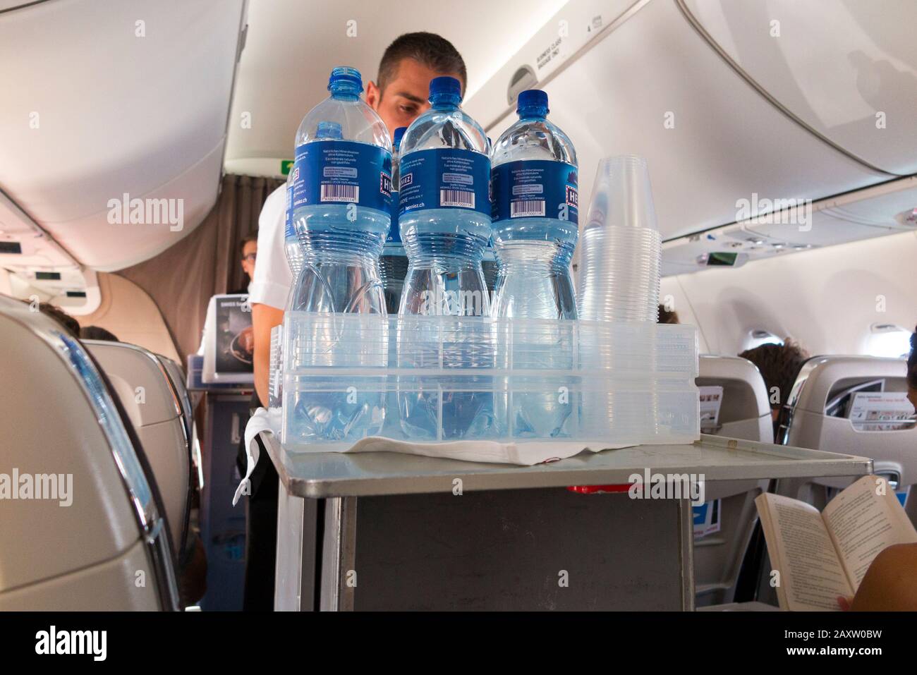 Member of cabin crew with water drinks trolley delivers refreshments to ...