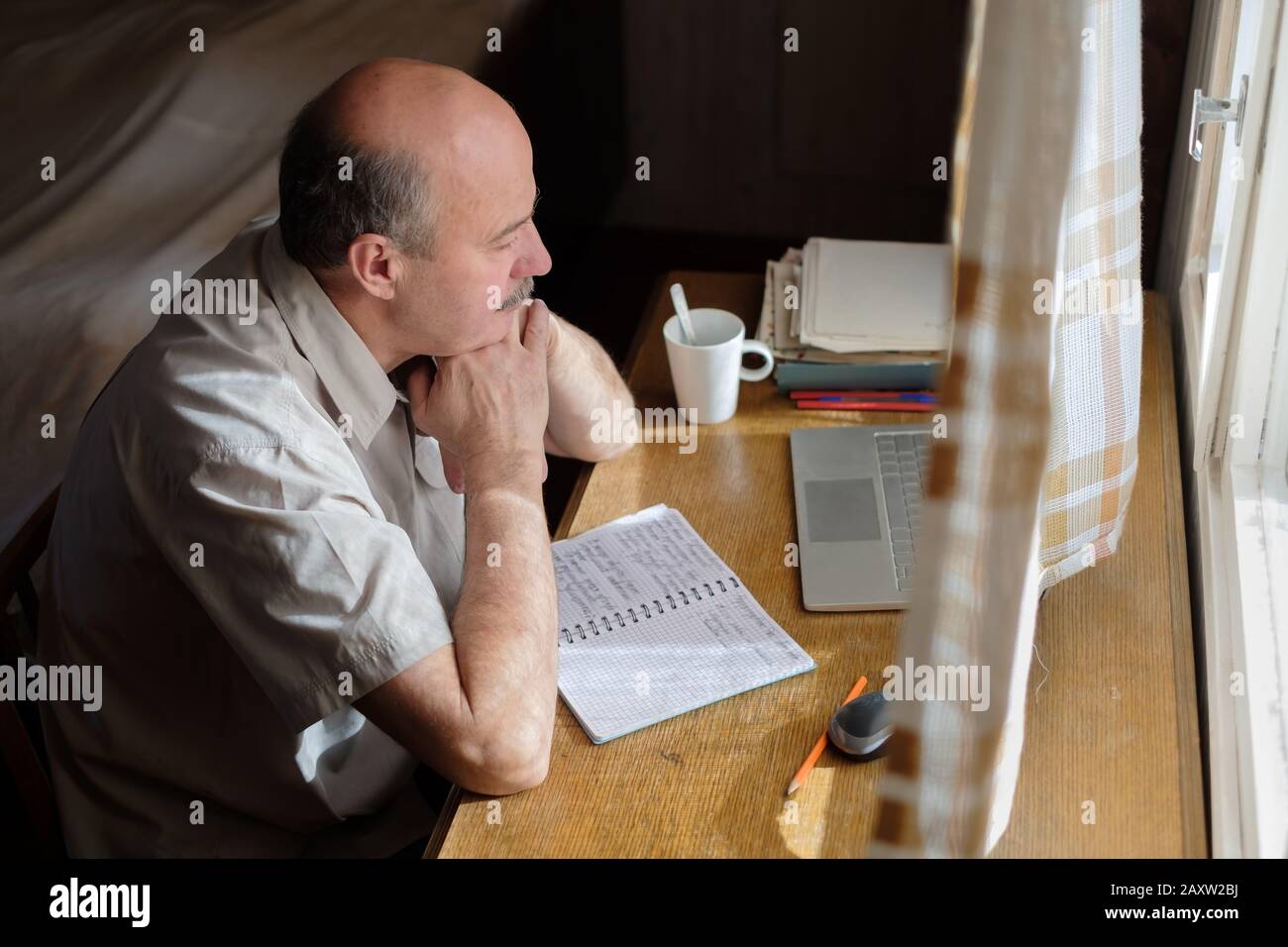 Senior man is writing in his room dreaming sitting near window. Diary ...