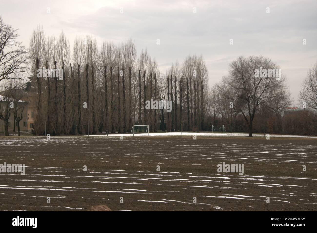 Trees and two football goals in a field with snow during winter ...