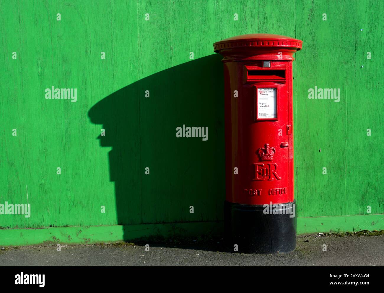 Red post box against green building site hoarding, Coventry, UK Stock ...